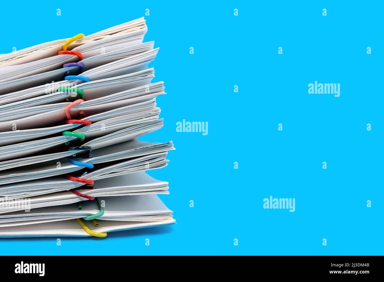 A stack of paper with colored pins on a blue background. Paper with ...