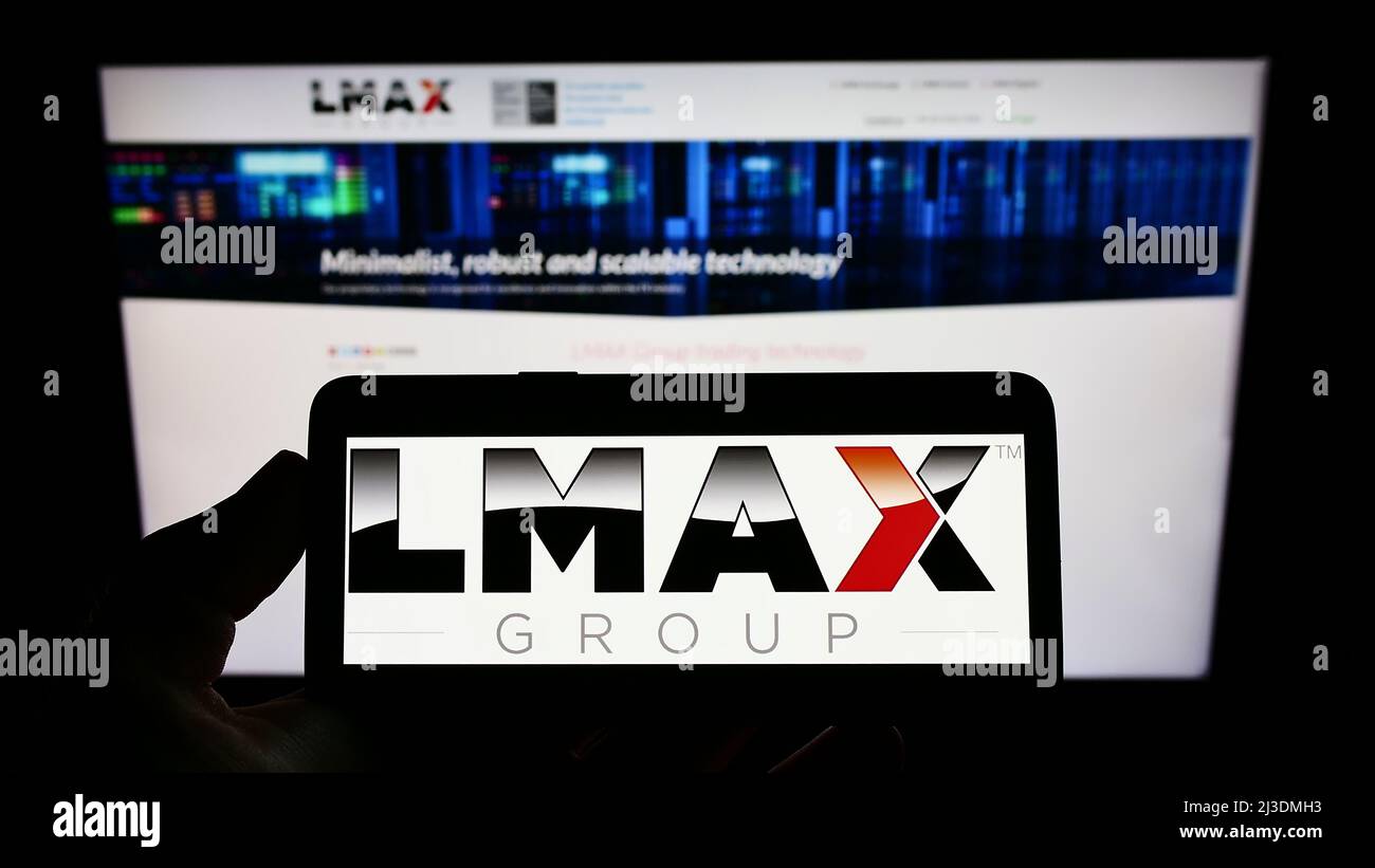Person holding smartphone with logo of British fintech company LMAX ...