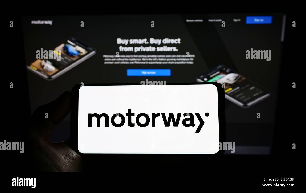 Person holding mobile phone with logo of British car dealer company ...