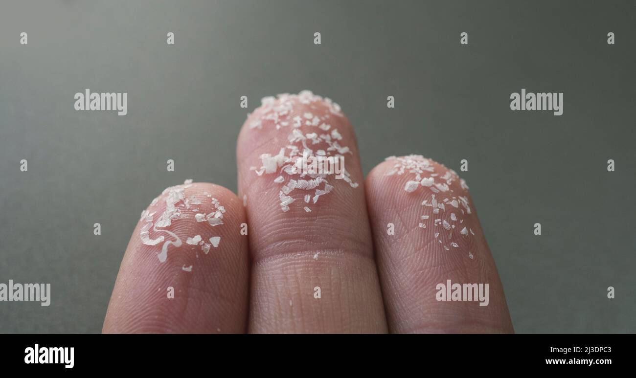 Close-up side shot of microplastics on human fingers. Concept for water ...