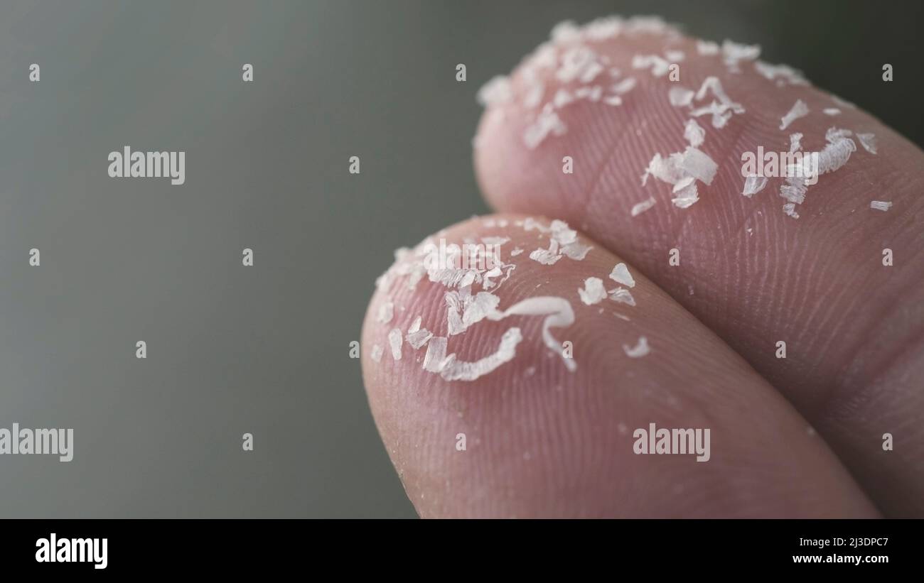 Close-up side shot of microplastics on human fingers. Concept for water ...