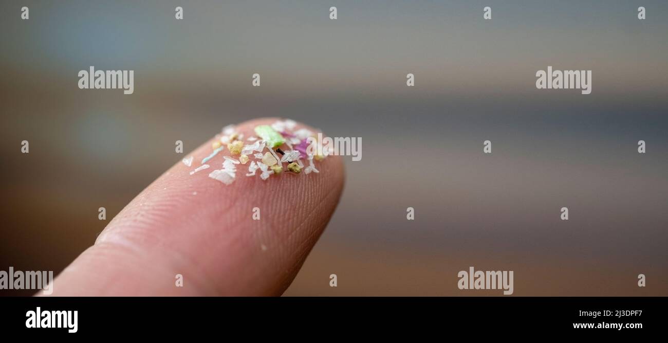 Close-up side shot of microplastics on human fingers. Concept for water ...