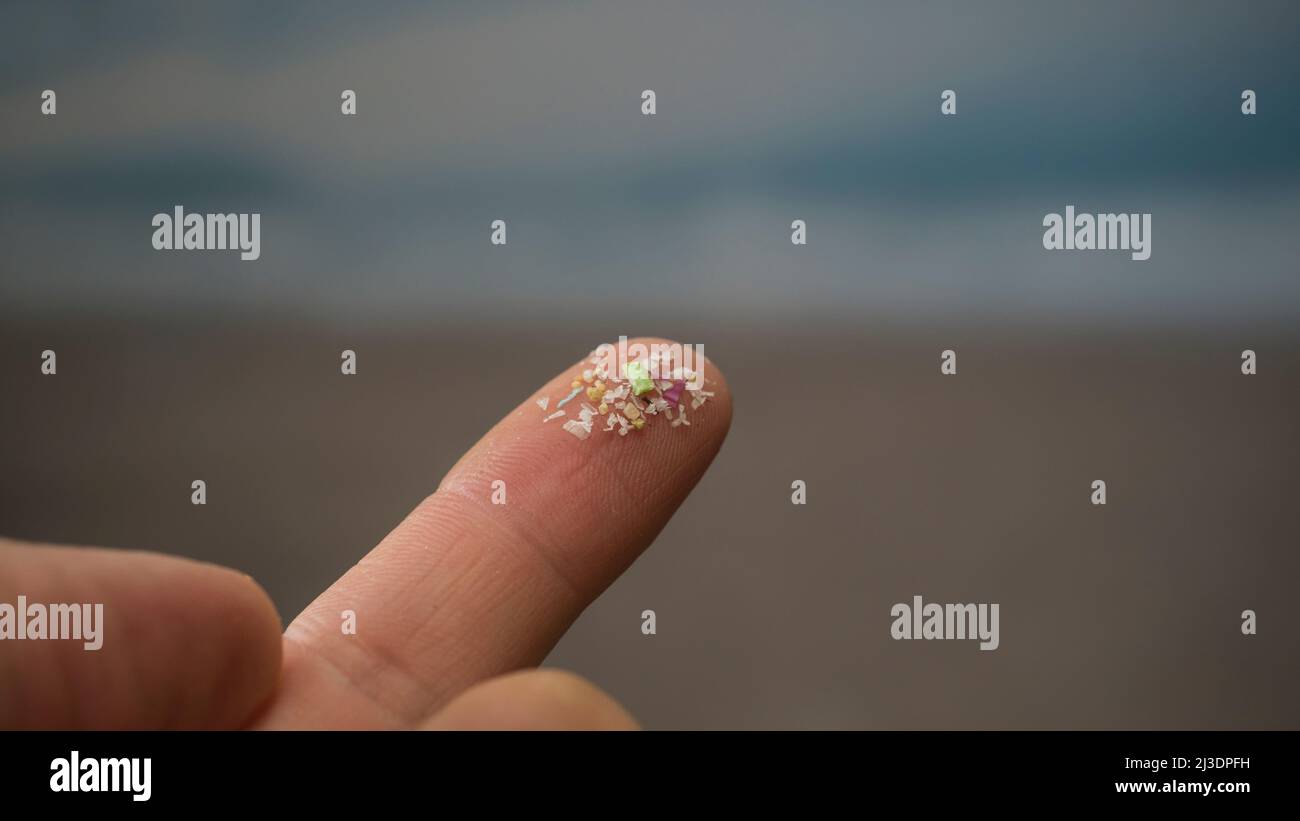 Close-up side shot of microplastics on human fingers. Concept for water ...