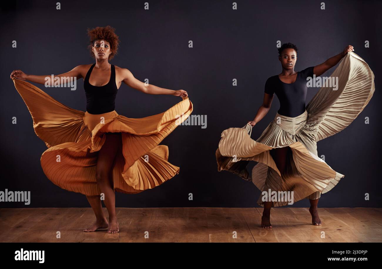 Feminine freedom. Two contemporary dancers with flowing skirts in front ...