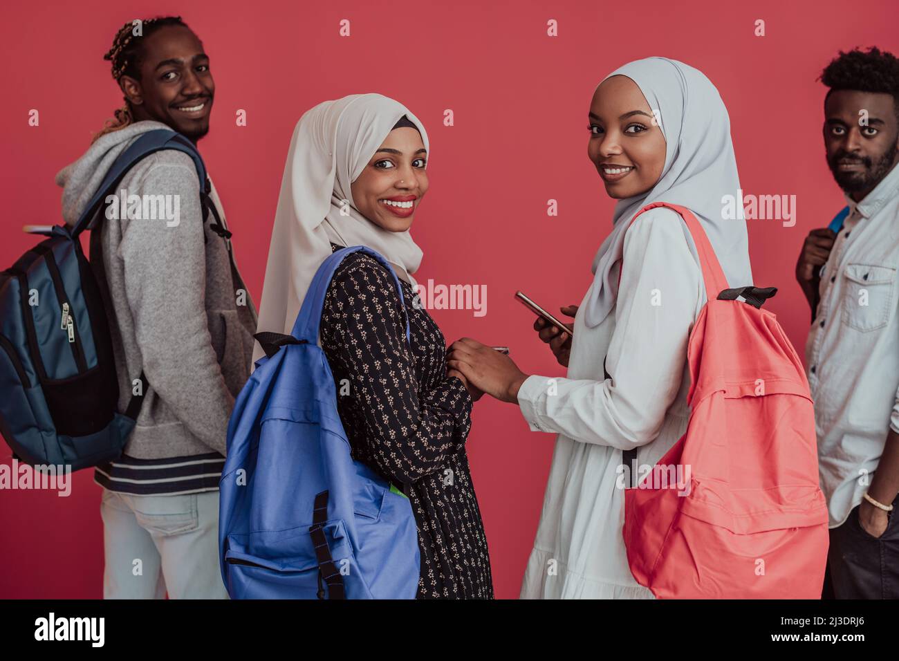 A group of African Muslim students with backpacks posing on a pink ...