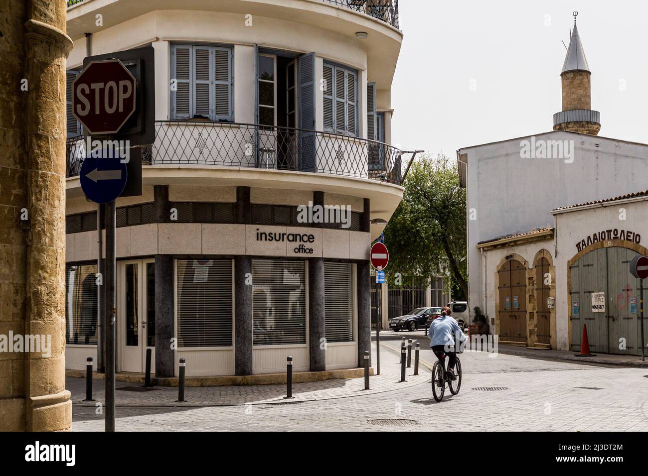 A woman rides a bicycle with a mosque in the background, Nicosia, Cyprus, on Apr. 7, 2022 ...