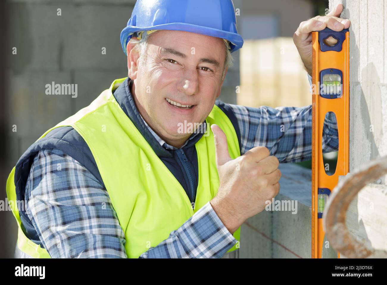 builder with spirit level on construction site wall Stock Photo - Alamy