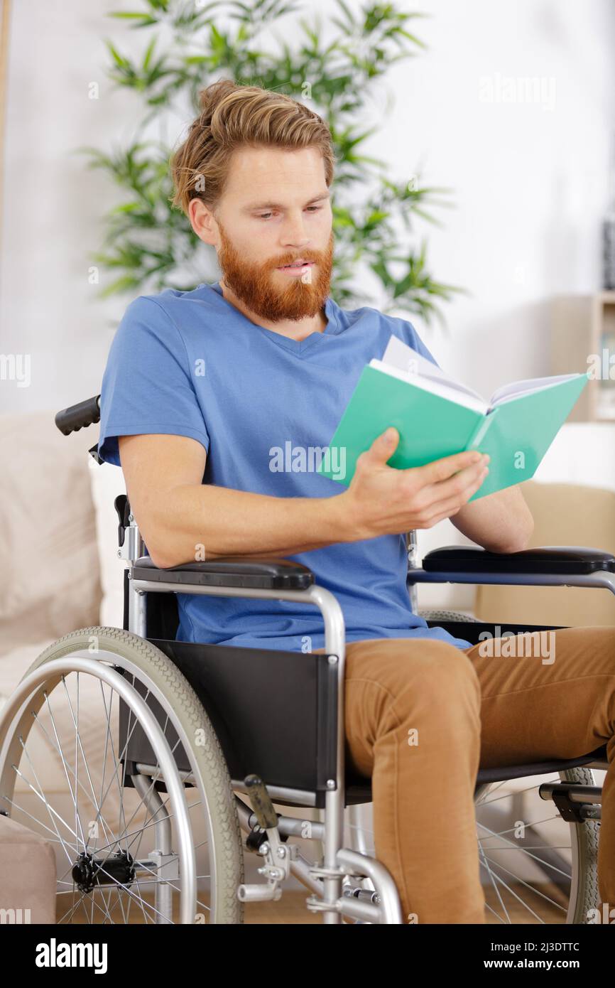 smiling disabled man on wheelchair reading book Stock Photo - Alamy