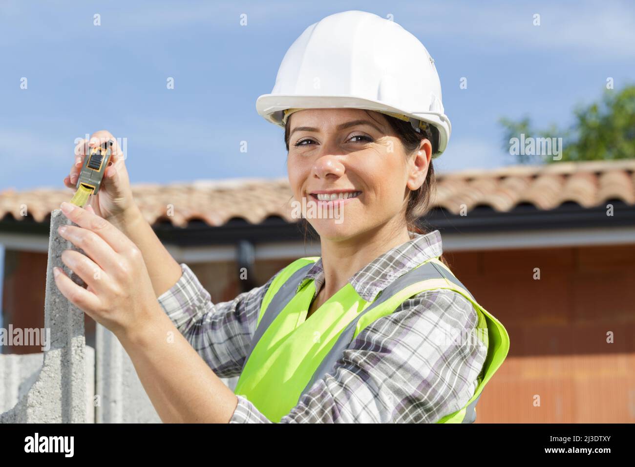 a happy female builder measuring outdoors Stock Photo - Alamy