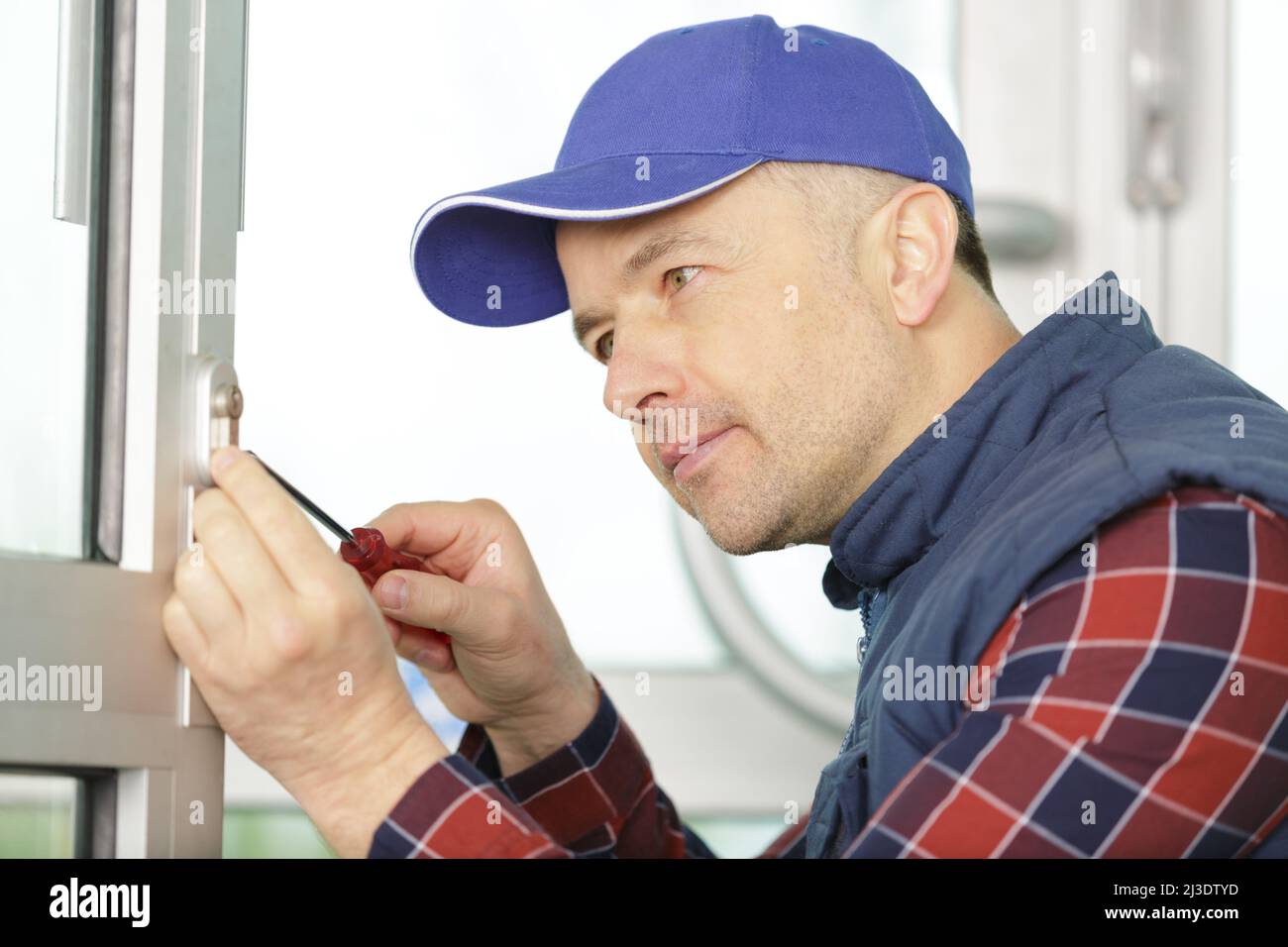 male repairman fixing window with screwdriver Stock Photo - Alamy