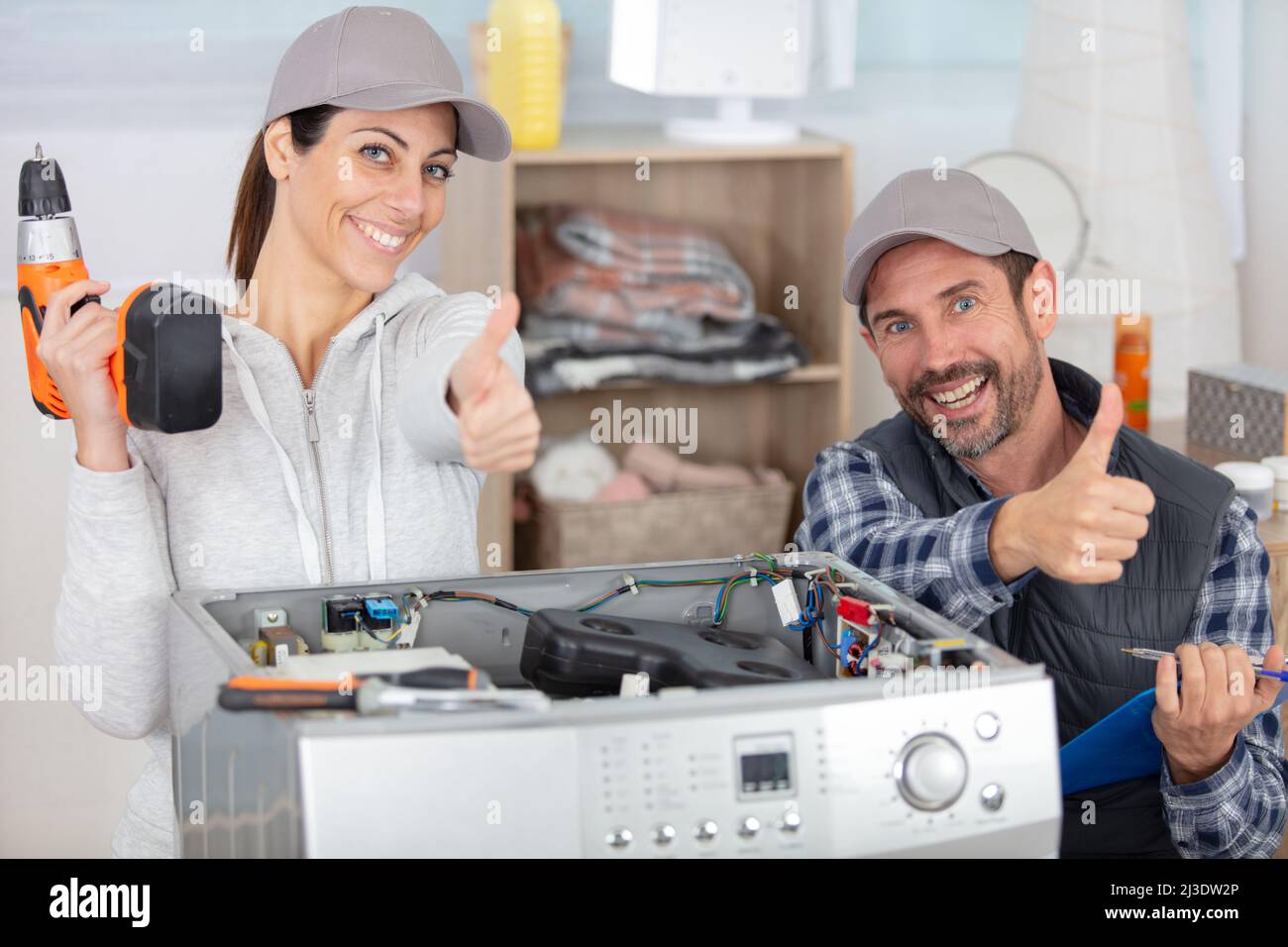 female male repairers thumb up wahsing machine Stock Photo - Alamy