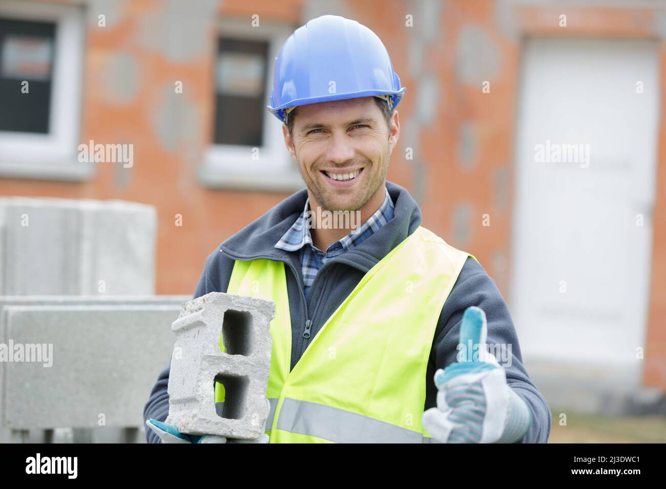 optimistic worker builder shows thumb up Stock Photo - Alamy