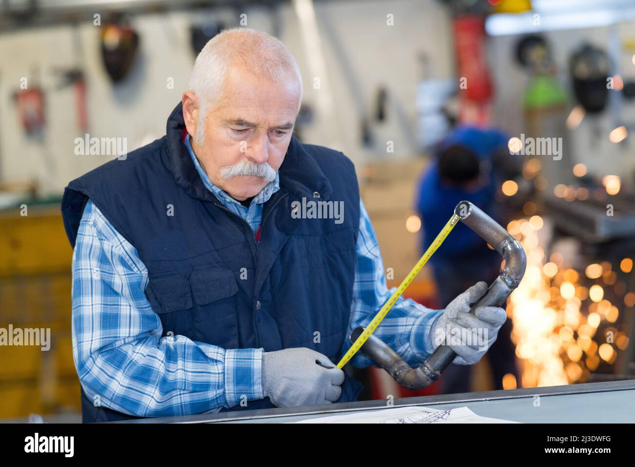 senior carpenter taking measurement on a wooden plank in workshop Stock ...
