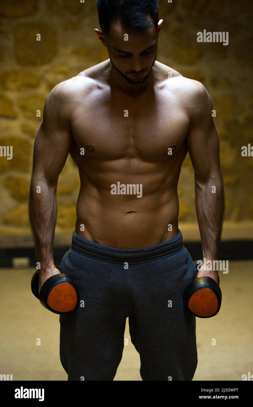 young muscular man holding the weights in gym Stock Photo - Alamy