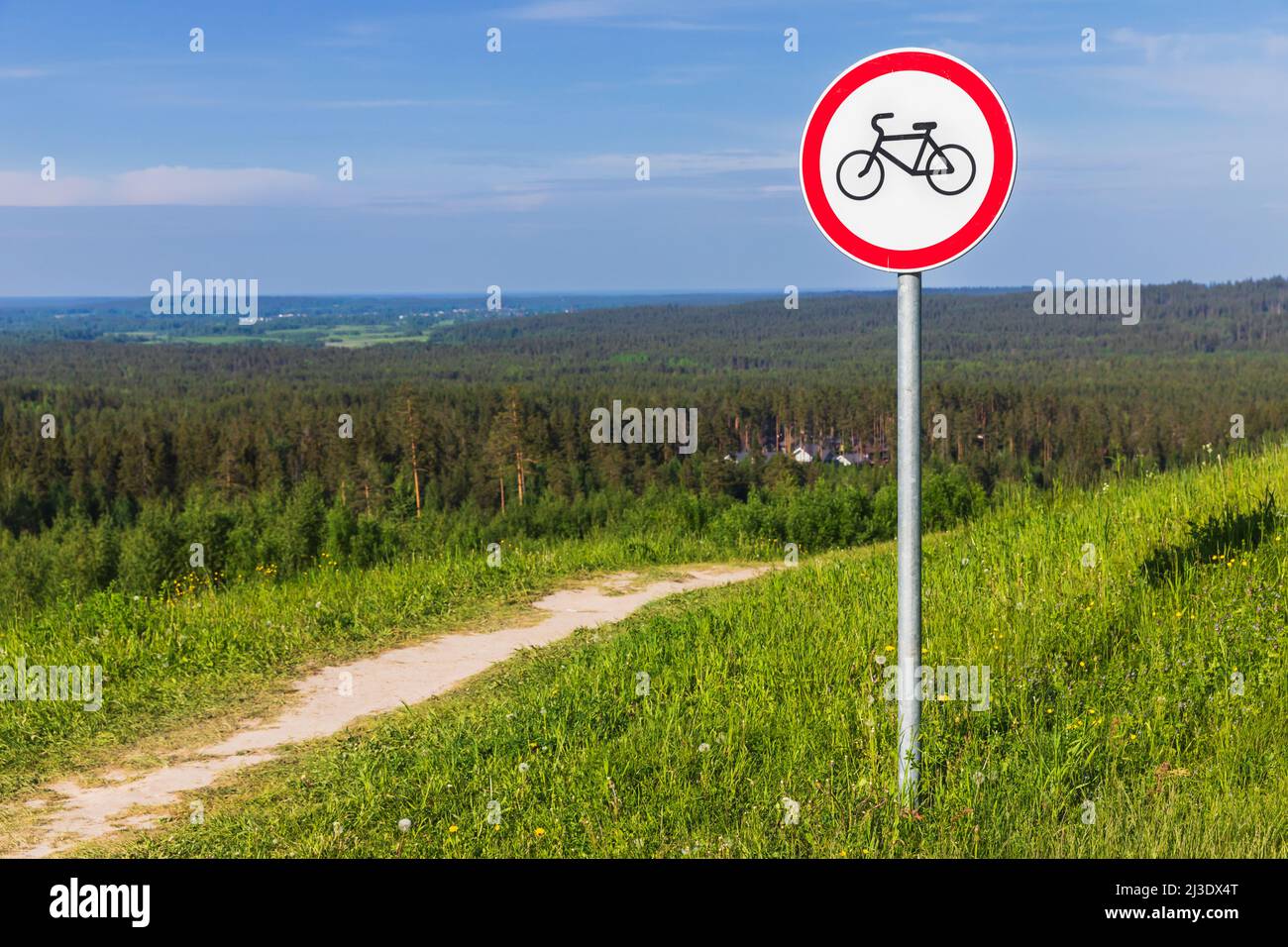 No bikes. Round prohibition road sign mounted on pole near rural road ...