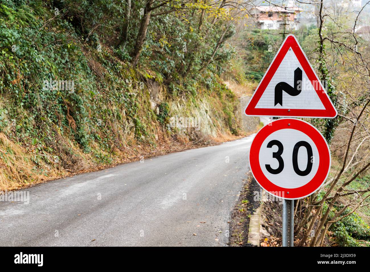Dangerous turns and speed limit road signs mounted on metal pole near ...
