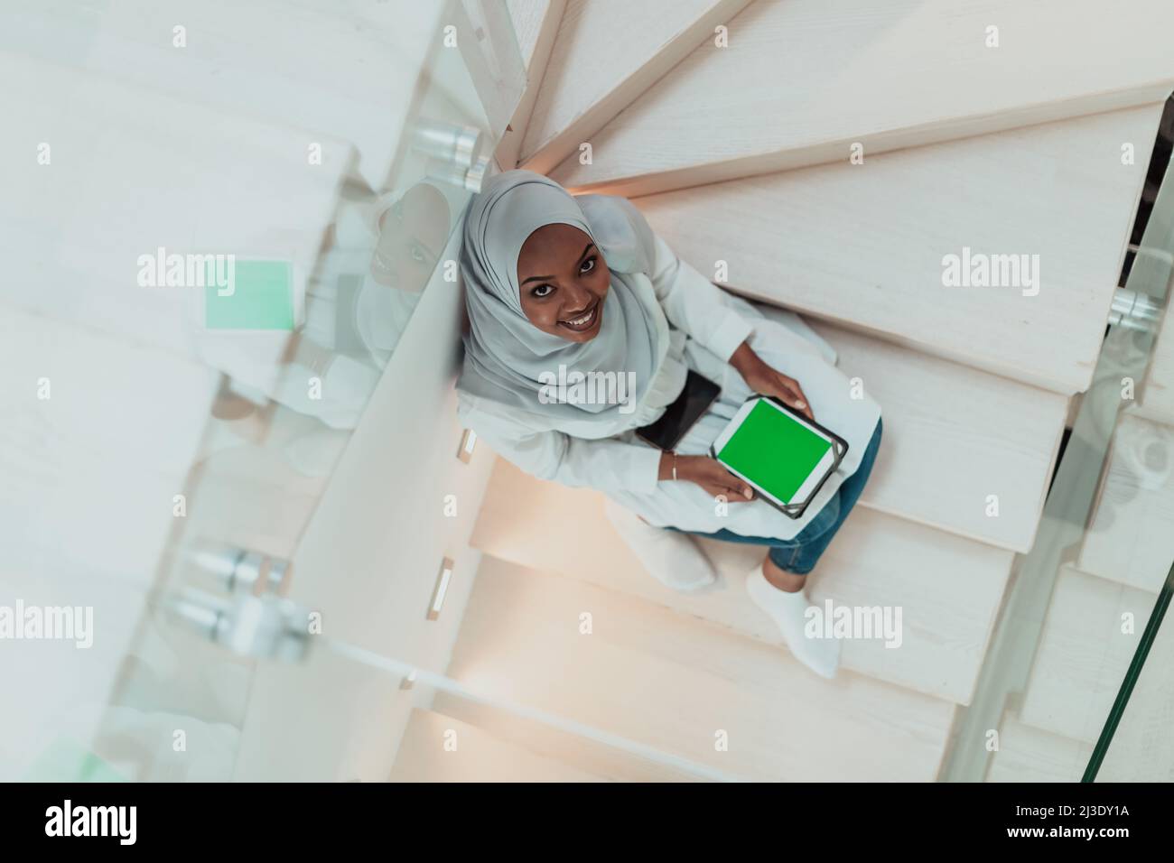 Young african modern muslim woman using tablet computer while sitting ...