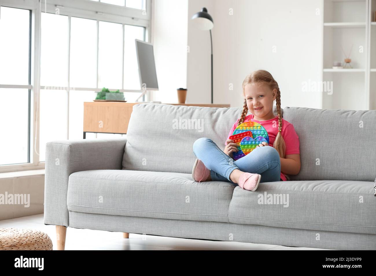 Pretty girl sitting on sofa and holding different pop it fidget toys in ...