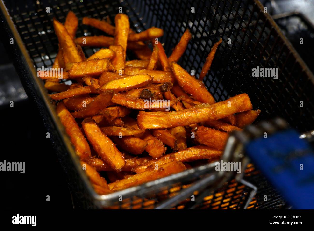 deep fried potato fries ( sweet potato ) in a fat frying basket ...