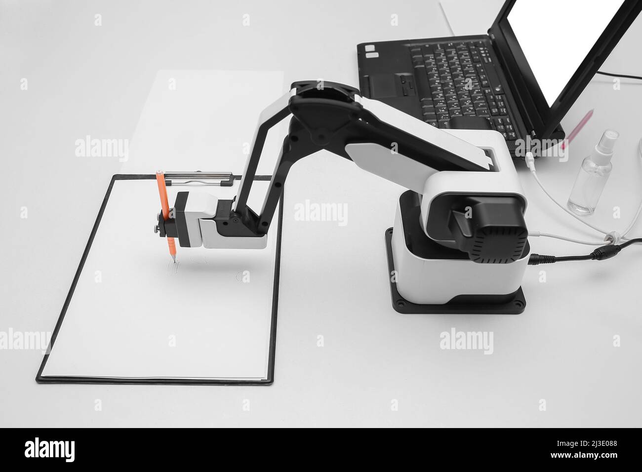Futuristic robotic arm with pen and blank paper sheet at exhibition ...