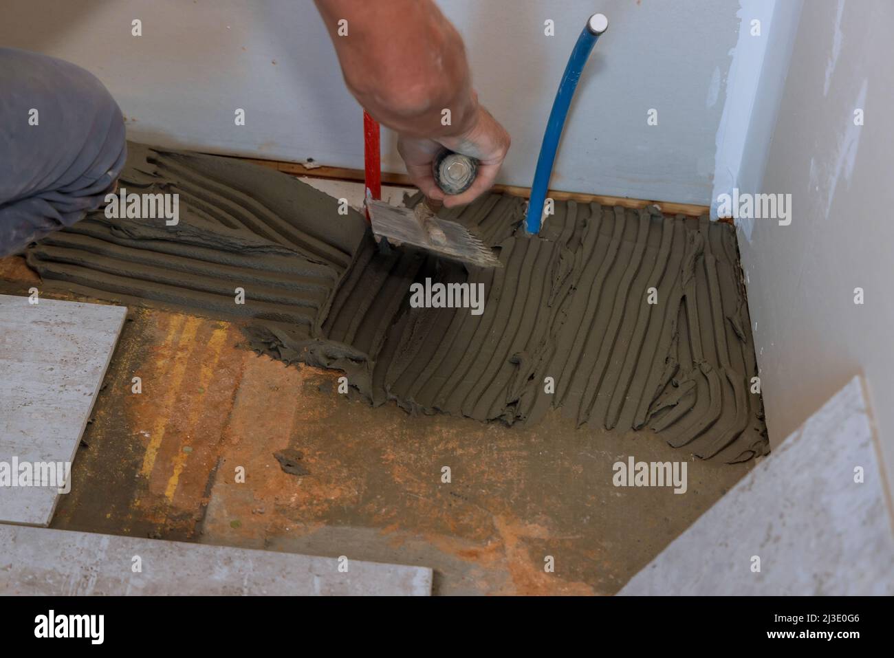 Worker applying tile adhesive on the floor Stock Photo - Alamy