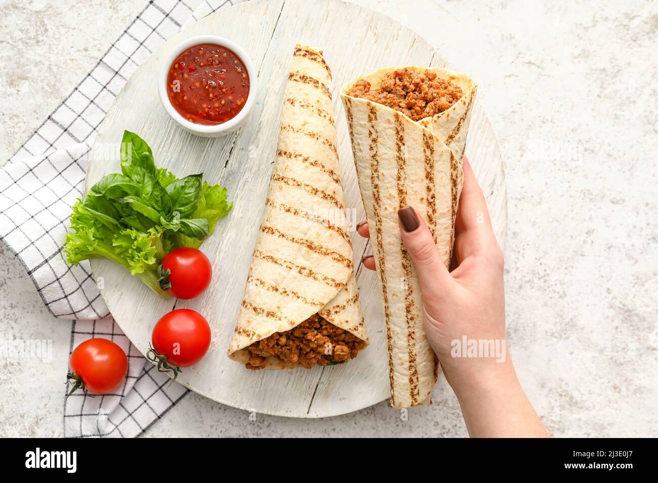 Female hand with tasty burritos and sauce on light background Stock ...
