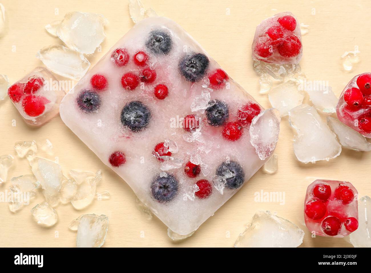 Fresh fruits frozen in ice on beige background Stock Photo - Alamy