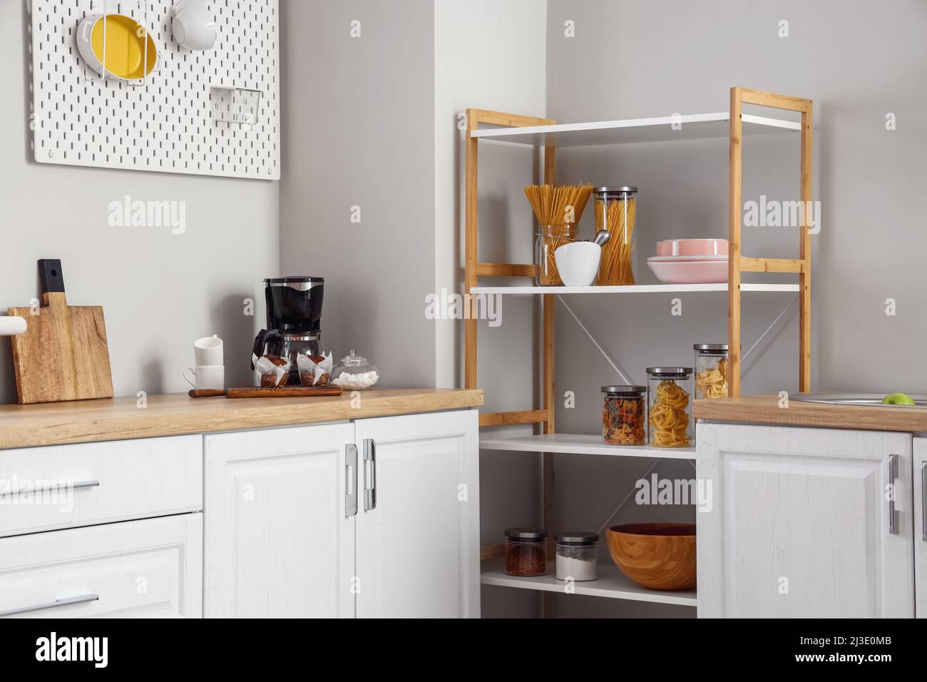 Modern shelving unit and counter with coffee maker near light wall in ...