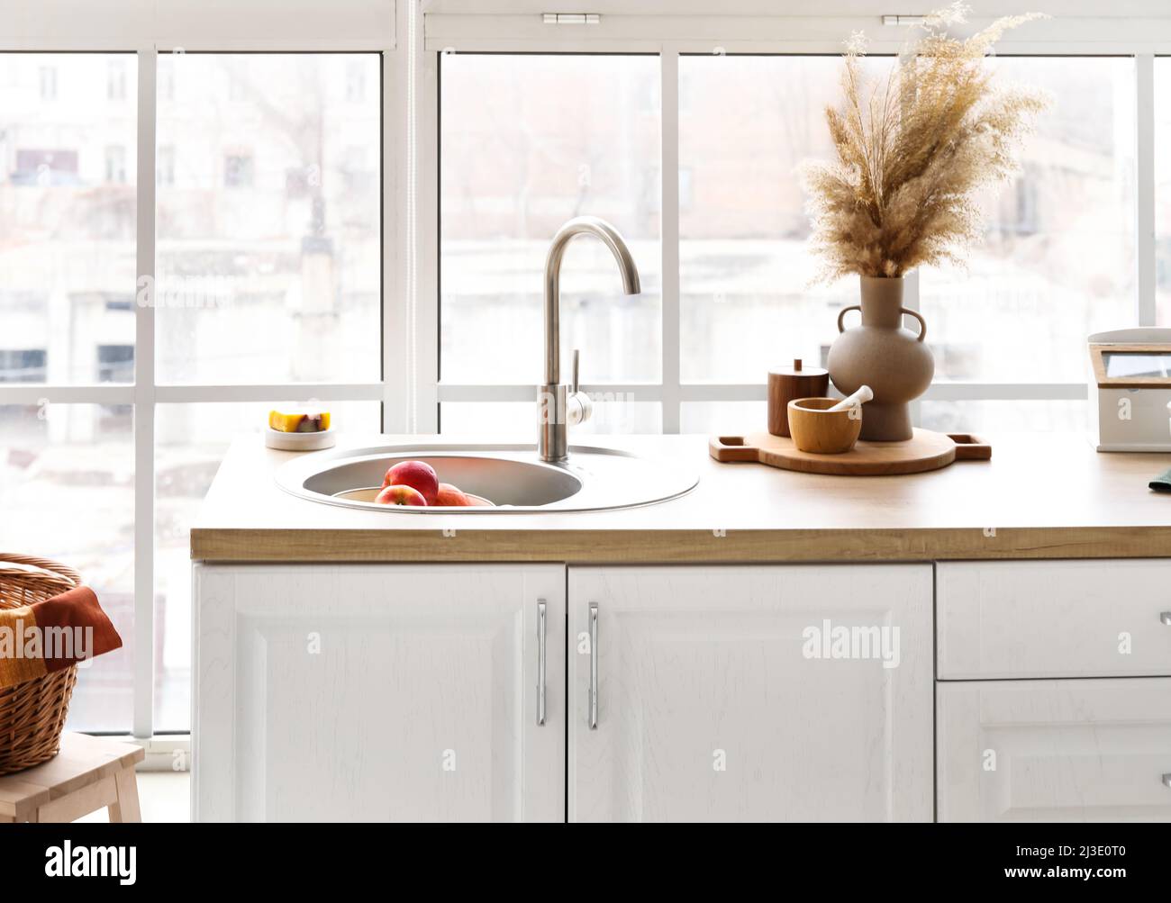 Wooden counter with sink, vase and cookware in light kitchen Stock ...