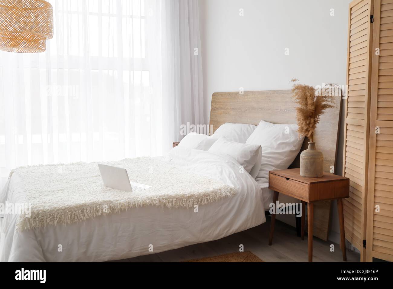 Comfortable bed with laptop in room Stock Photo - Alamy