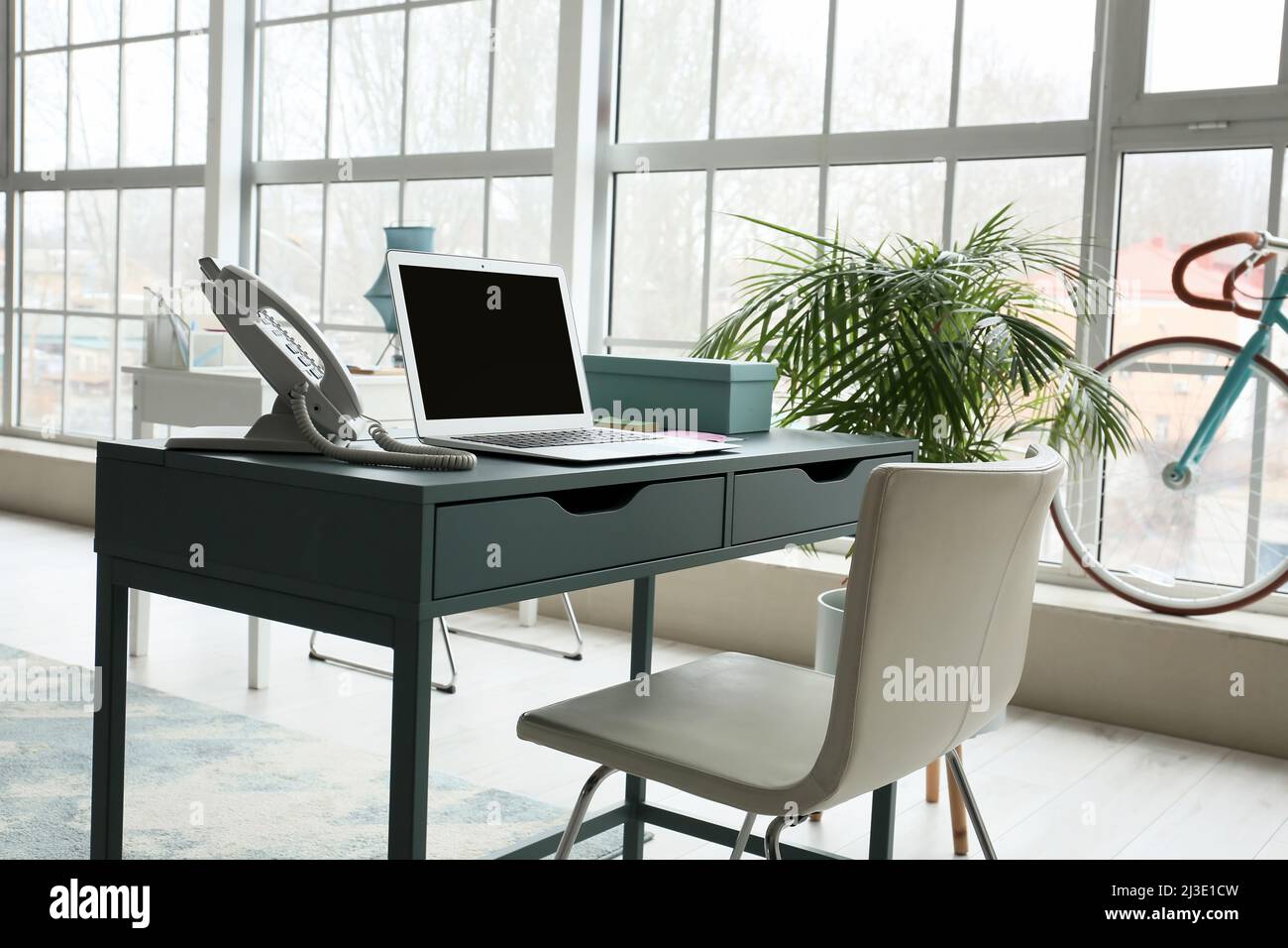 Workplace with modern laptop and landline phone in light office Stock ...