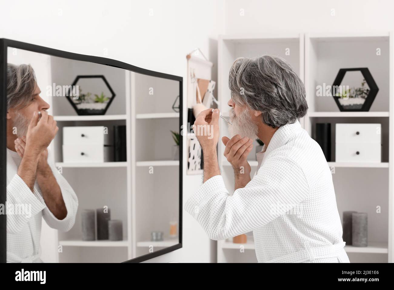 Mature man using serum for hair growth in bathroom Stock Photo - Alamy