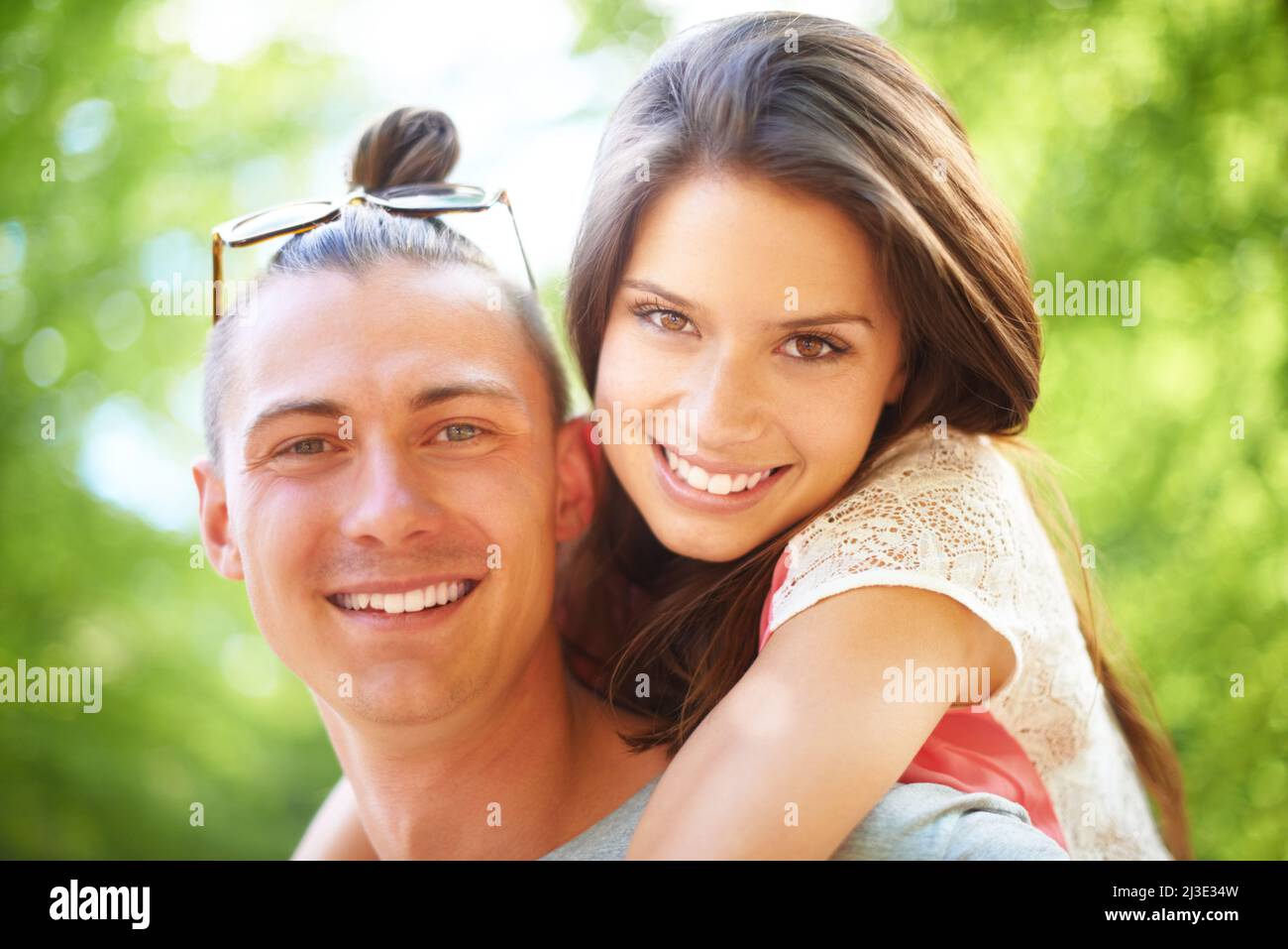 Young love. A trendy young man giving his girlfriend a piggyback ride ...