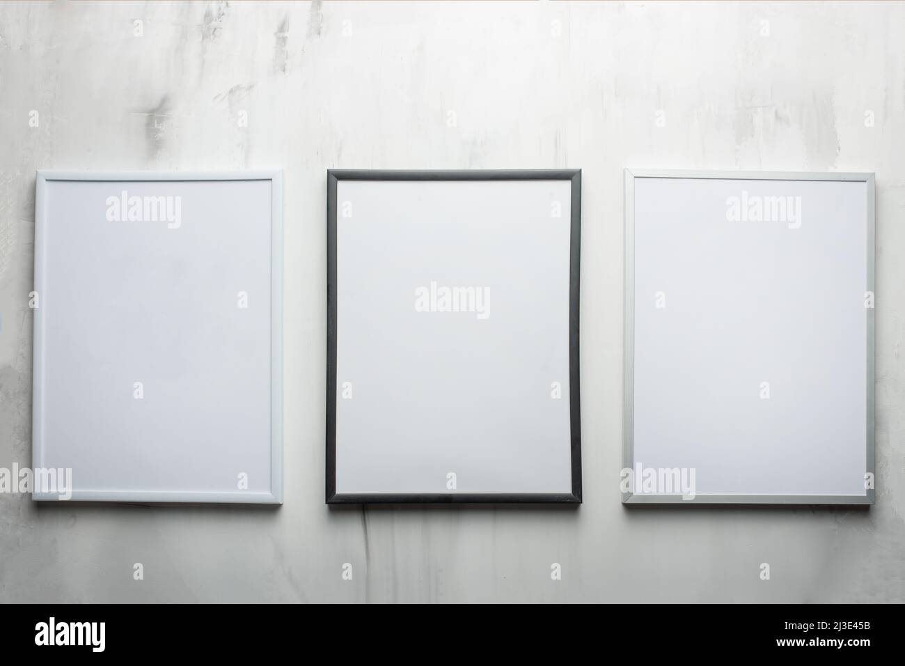Three white frames on the wall background. The concept of design and ...