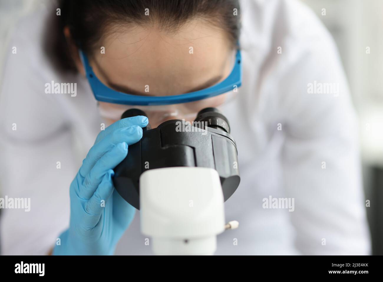 Woman doctor scientist looking through microscope in clinic Stock Photo ...
