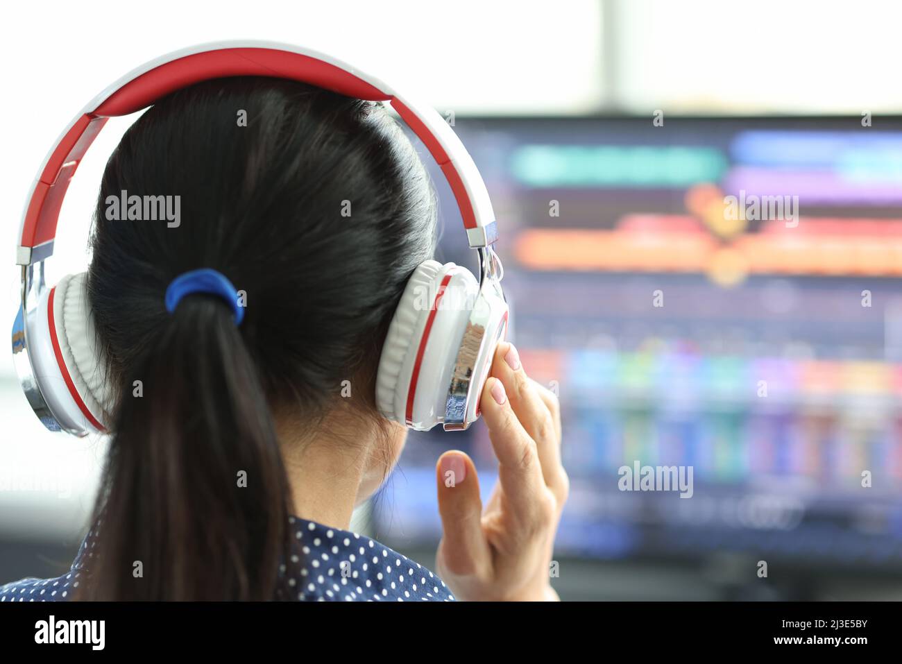 Woman in headphones in front of computer monitor Stock Photo - Alamy