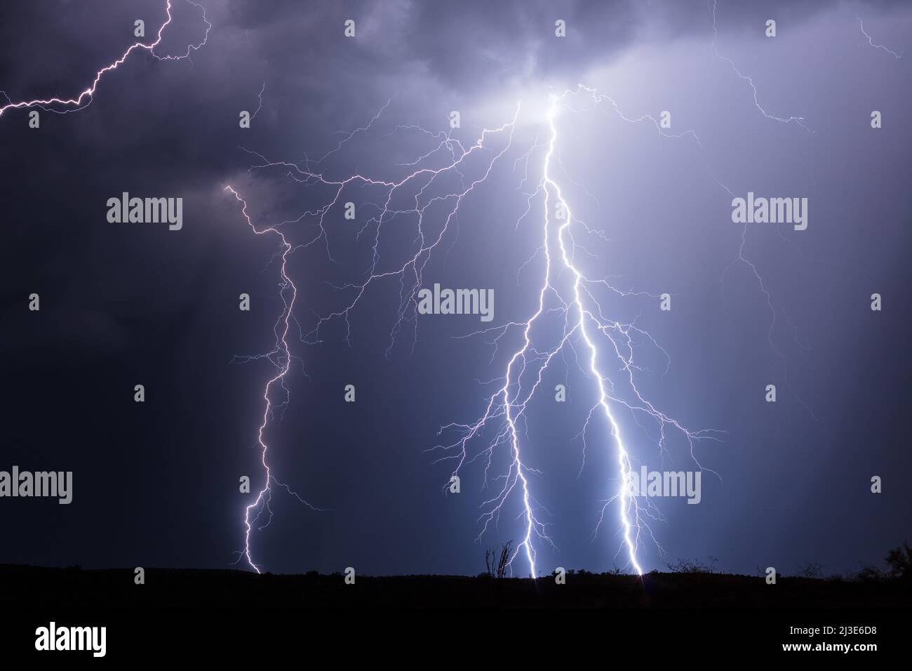 Bright lightning bolts illuminate the sky in a thunderstorm near ...