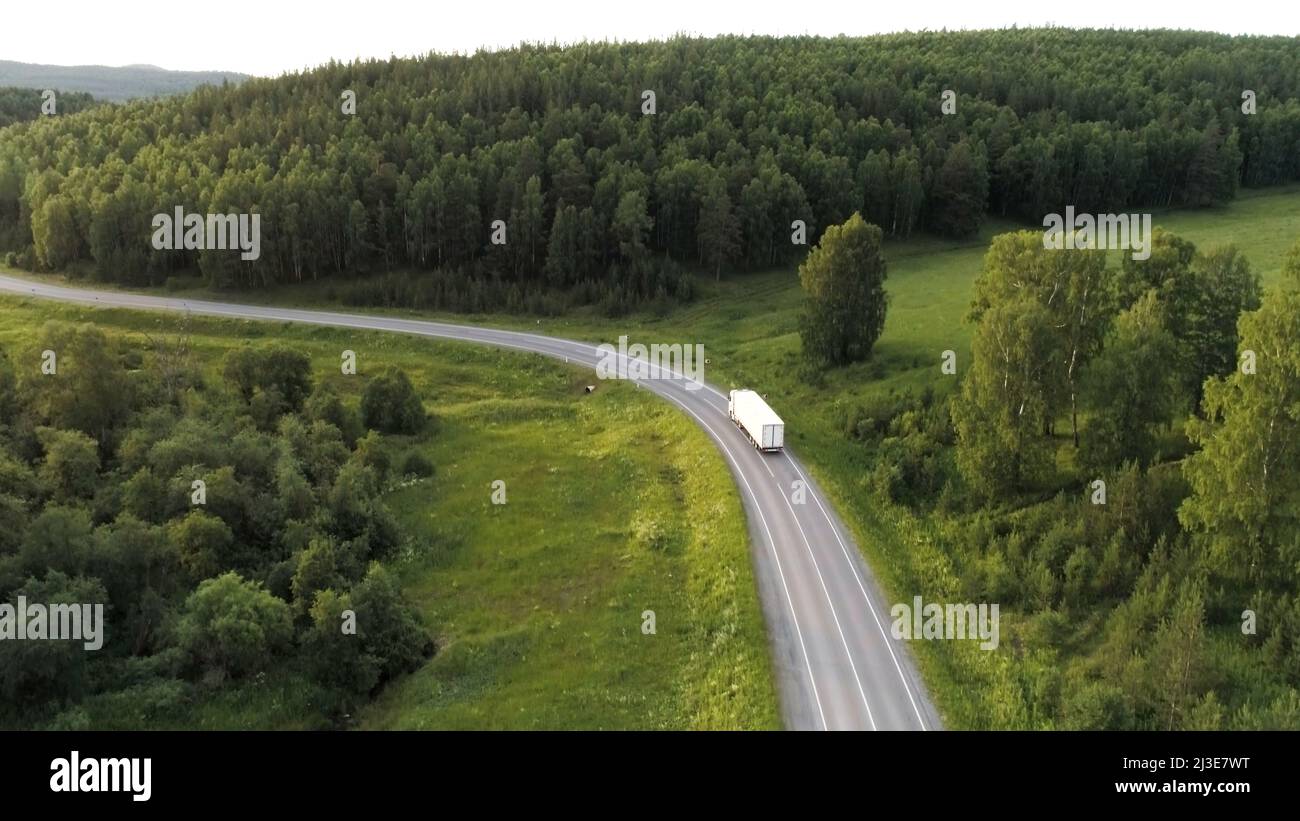Bird's-eye view.Scene.A large green forest next to the road on which a large white truck is ...