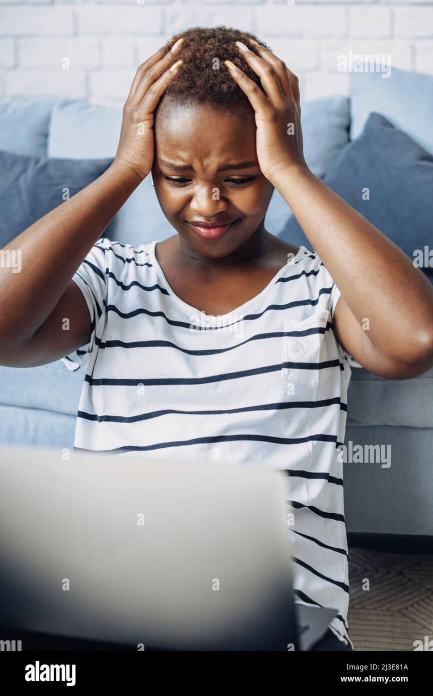 Frustrated African American woman with laptop emotionally reacting to ...