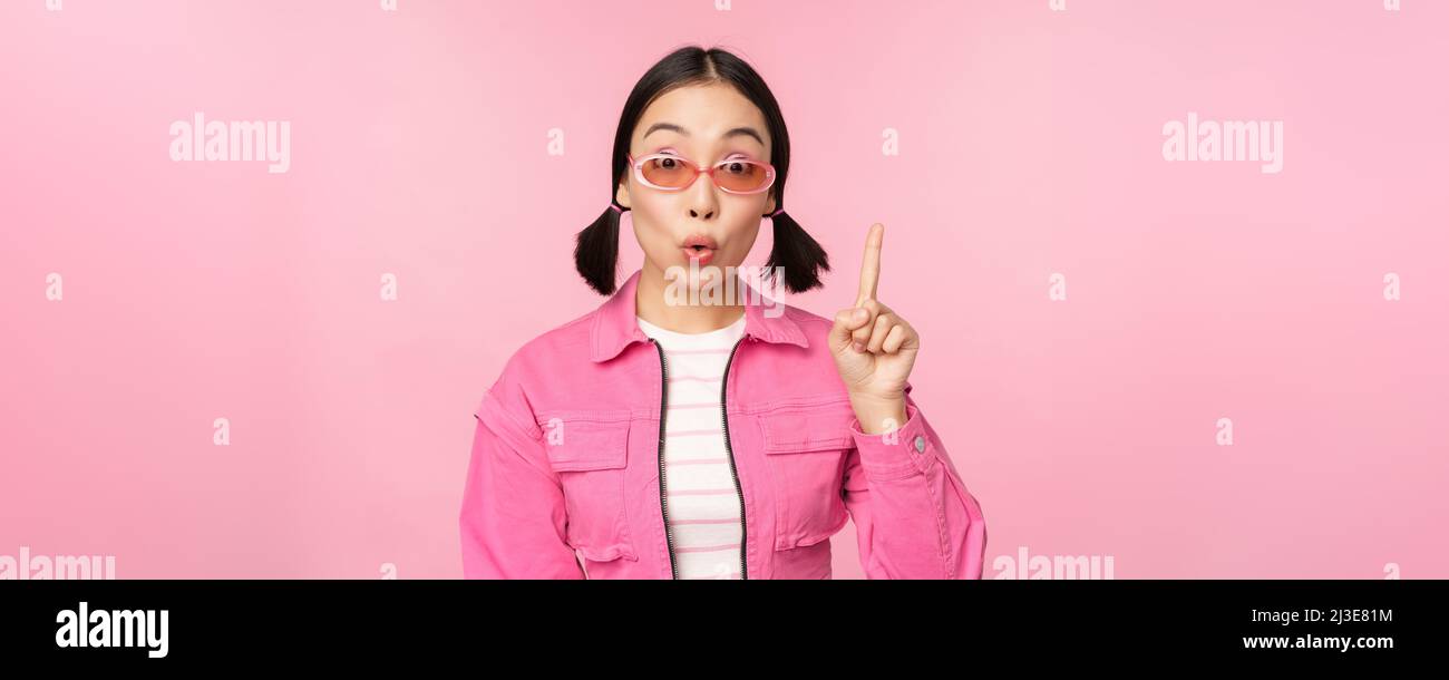 Cool and stylish asian girl, raising finger, pointing up, suggesting ...