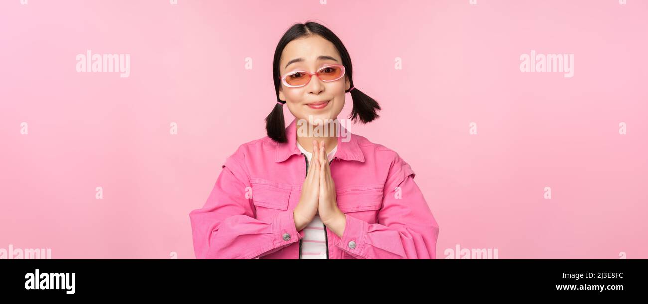 Please. Cute asian girl asking favour, begging, standing against studio ...
