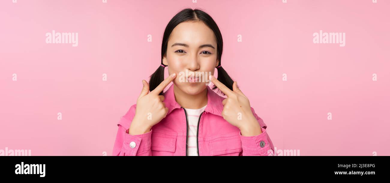 Close up portrait of young asian girl showing her dimples, poking ...