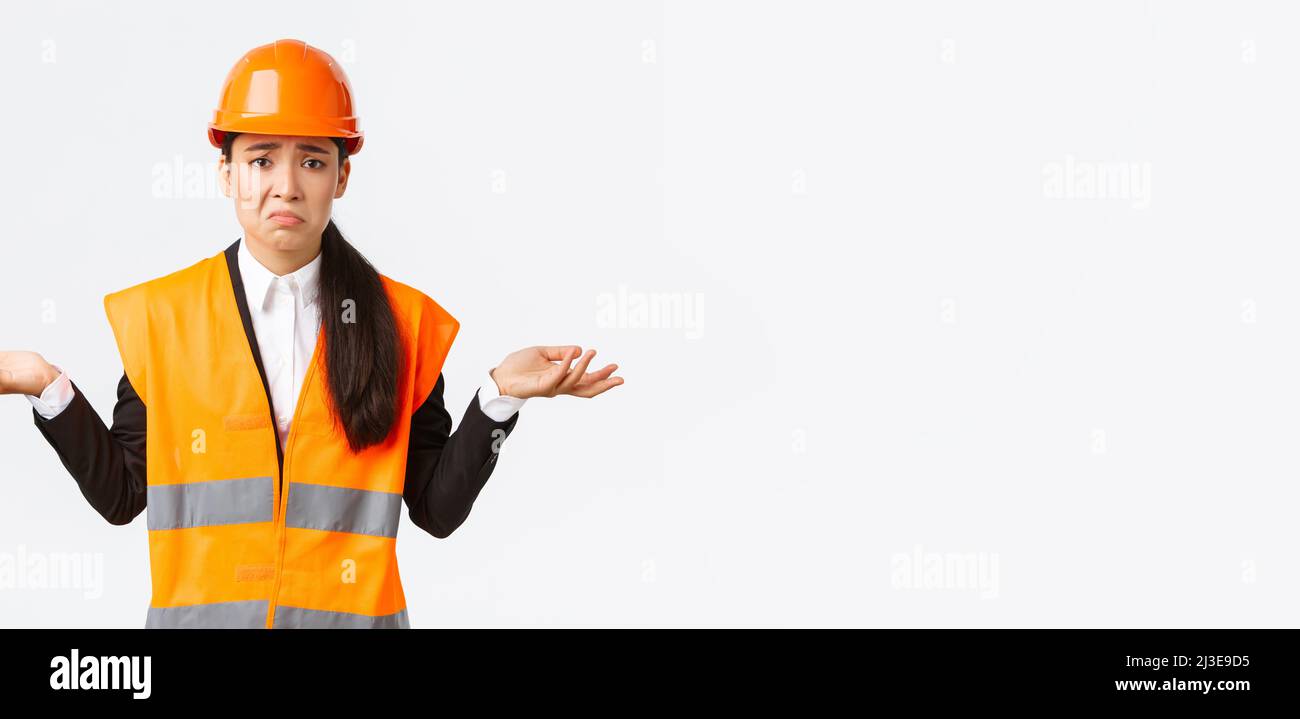 Upset and confused asian female engineer feeling complicated, raising ...