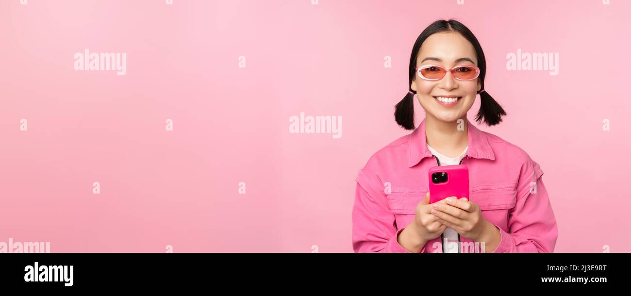 Portrait of korean girl in stylish sunglasses holding mobile phone ...