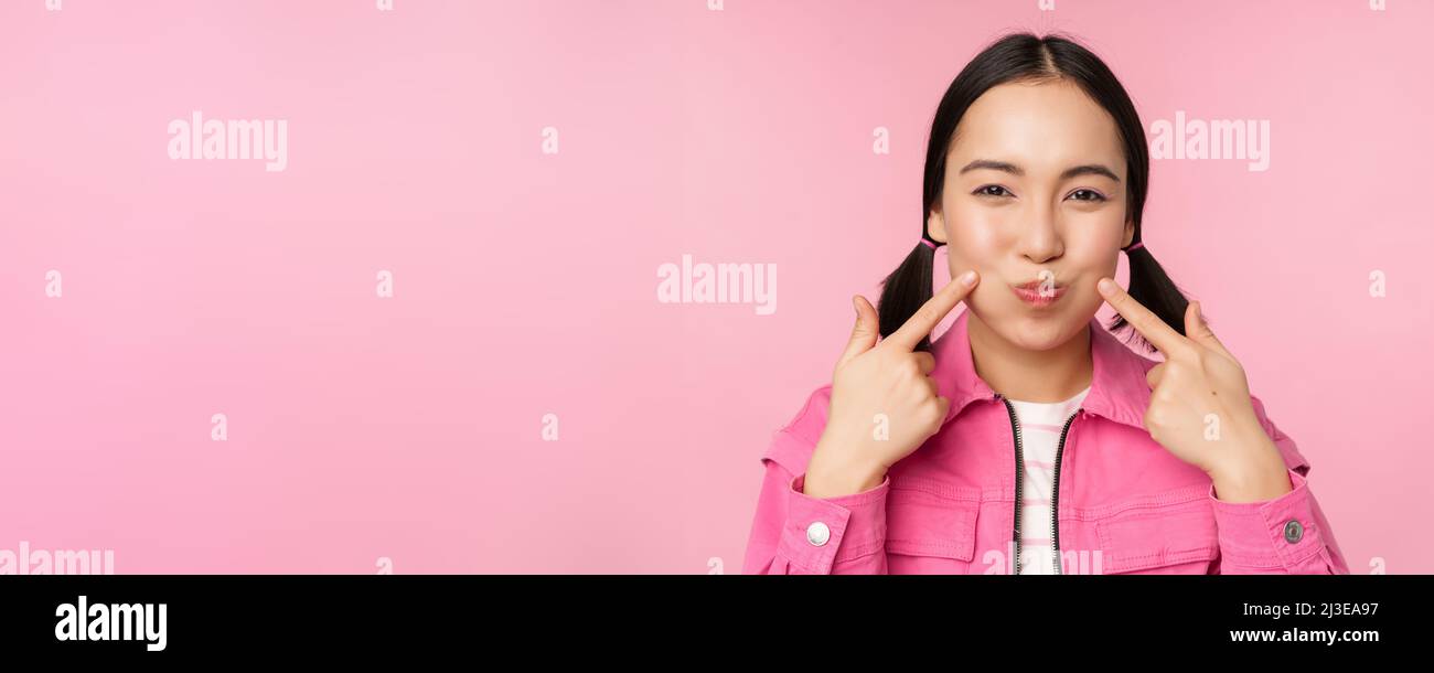 Close up portrait of young asian girl showing her dimples, poking ...