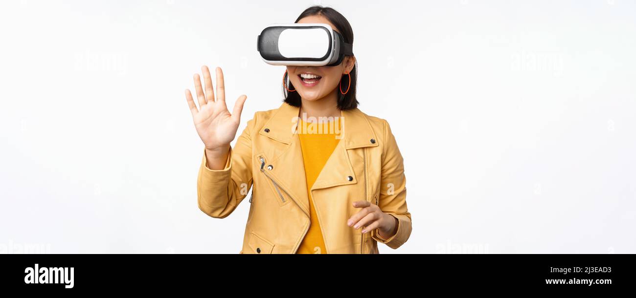 Happy asian girl in VR headset, saying hello in virtual reality chat ...
