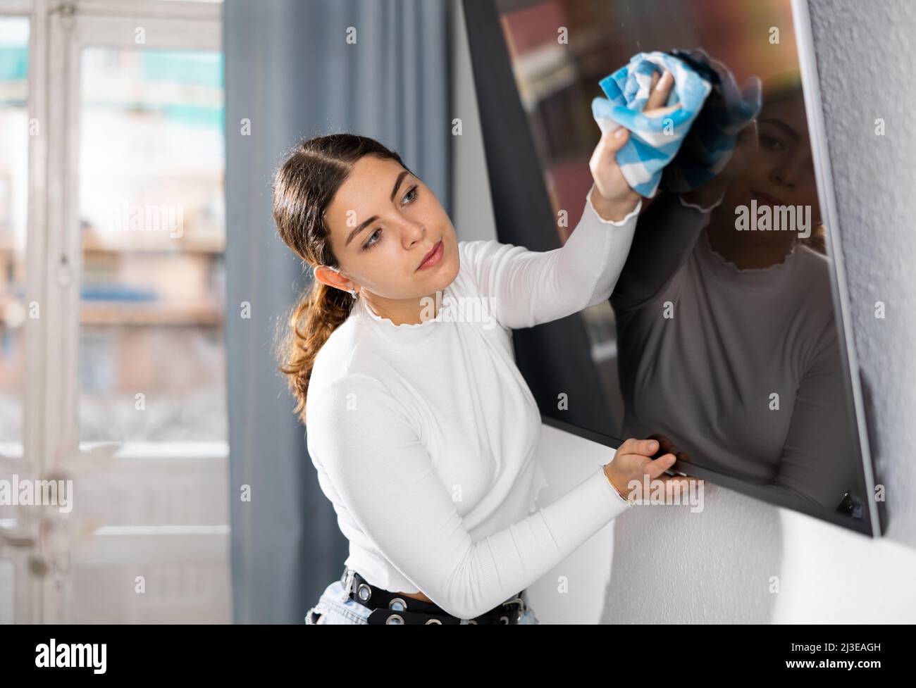 Woman cleaning TV screen in living room Stock Photo - Alamy