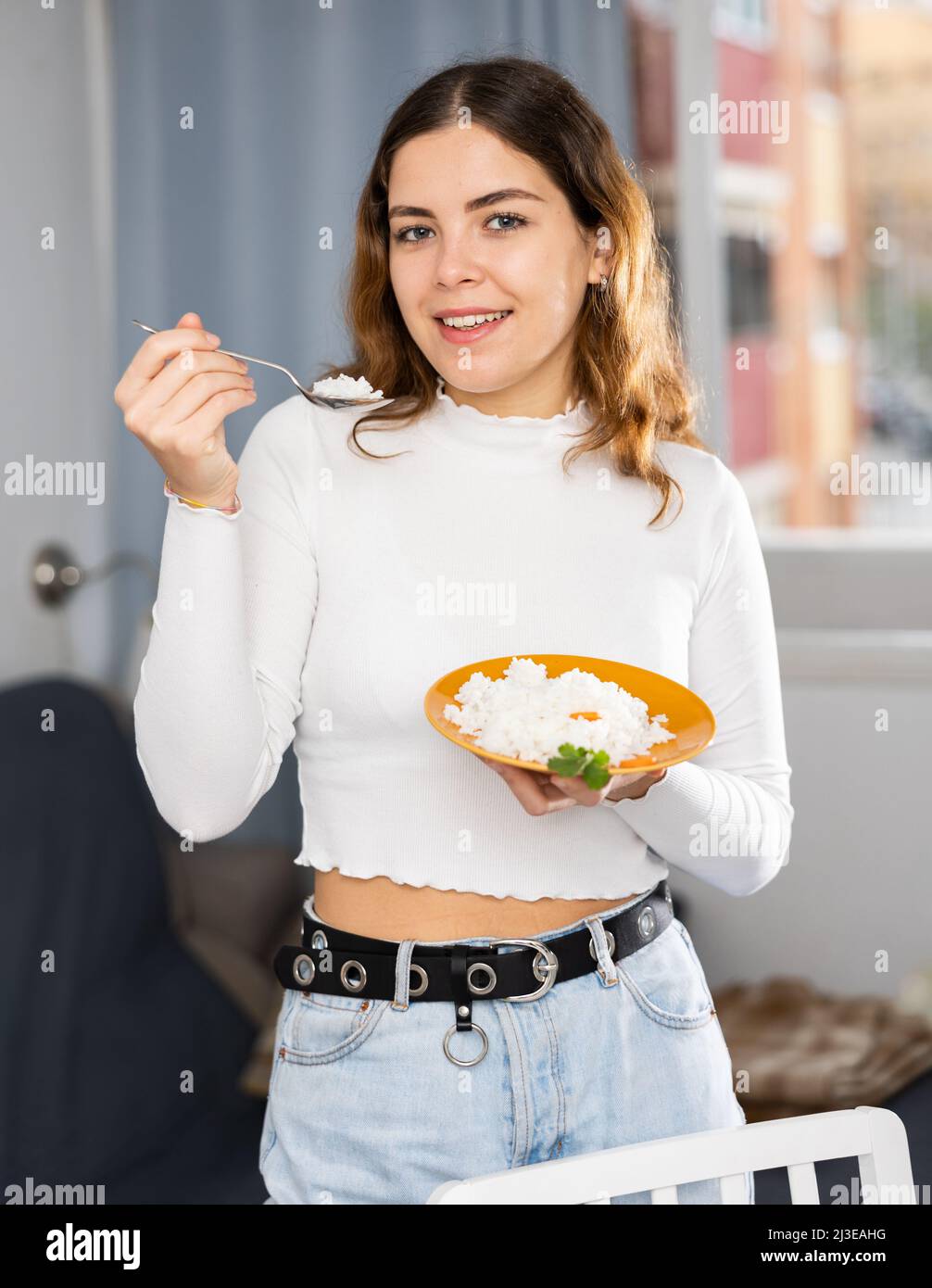 Emotional young woman eating rice at home Stock Photo - Alamy