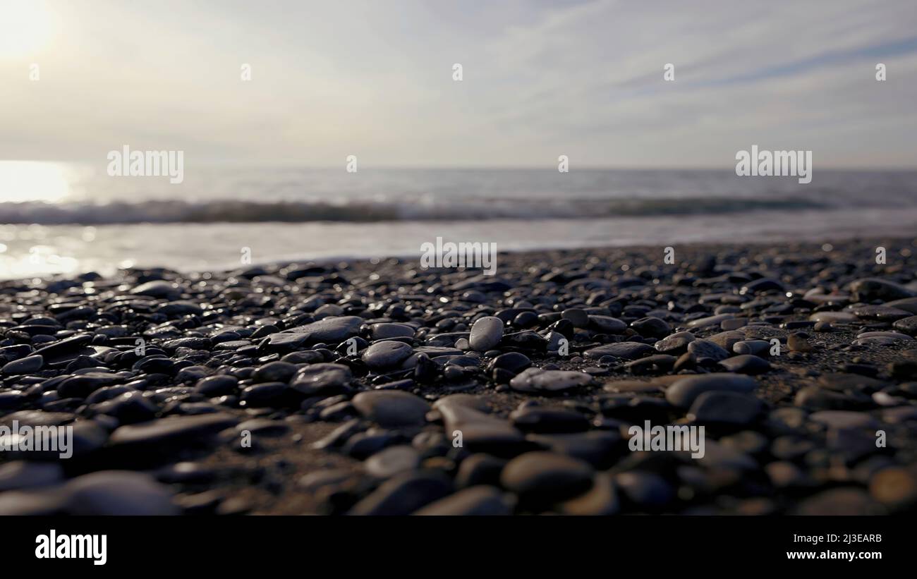 Pebble beach with small pebbles and sea waves. Action. Sea surface on ...
