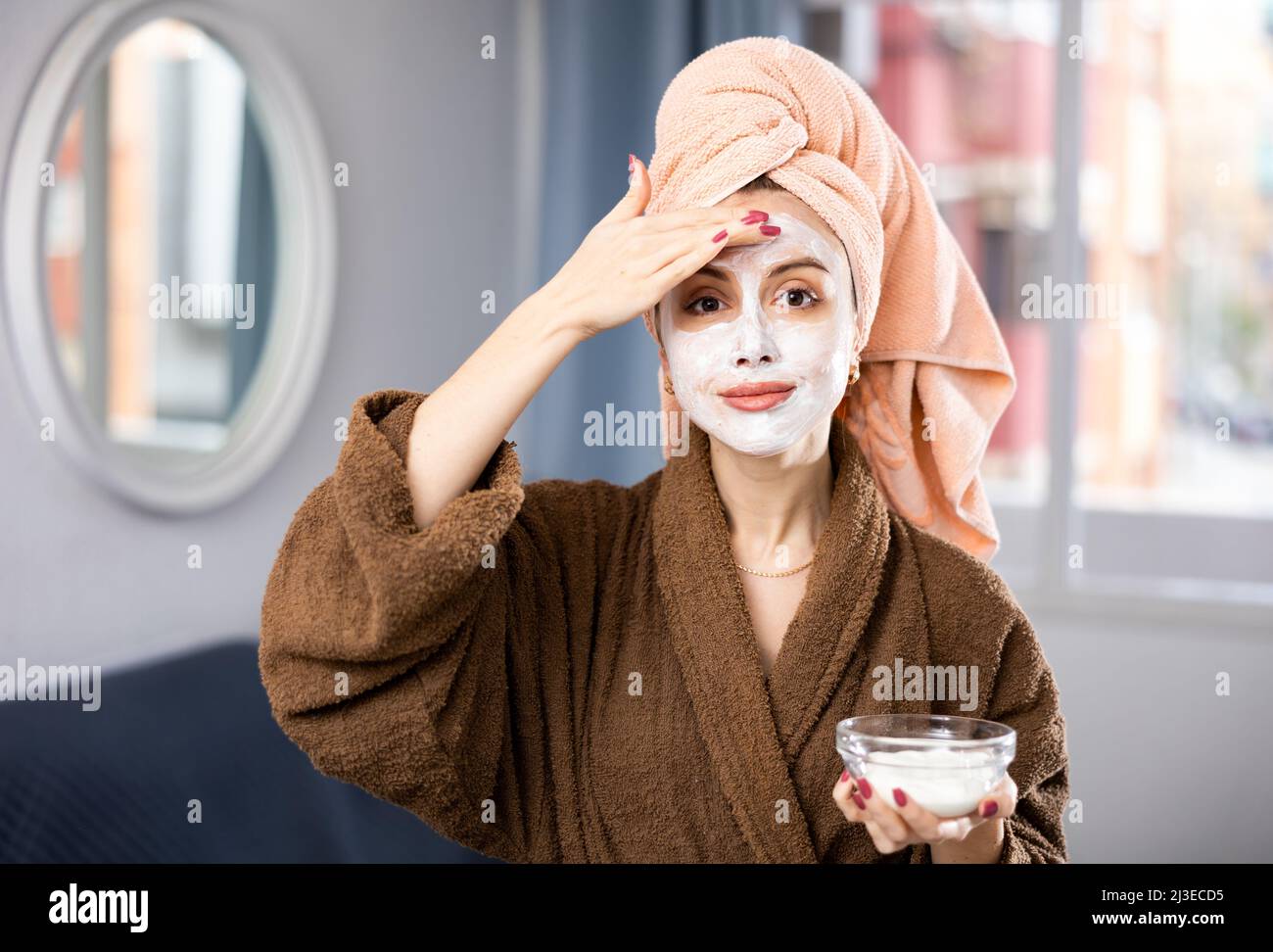 Happy woman taking care of face skin with lotion Stock Photo - Alamy
